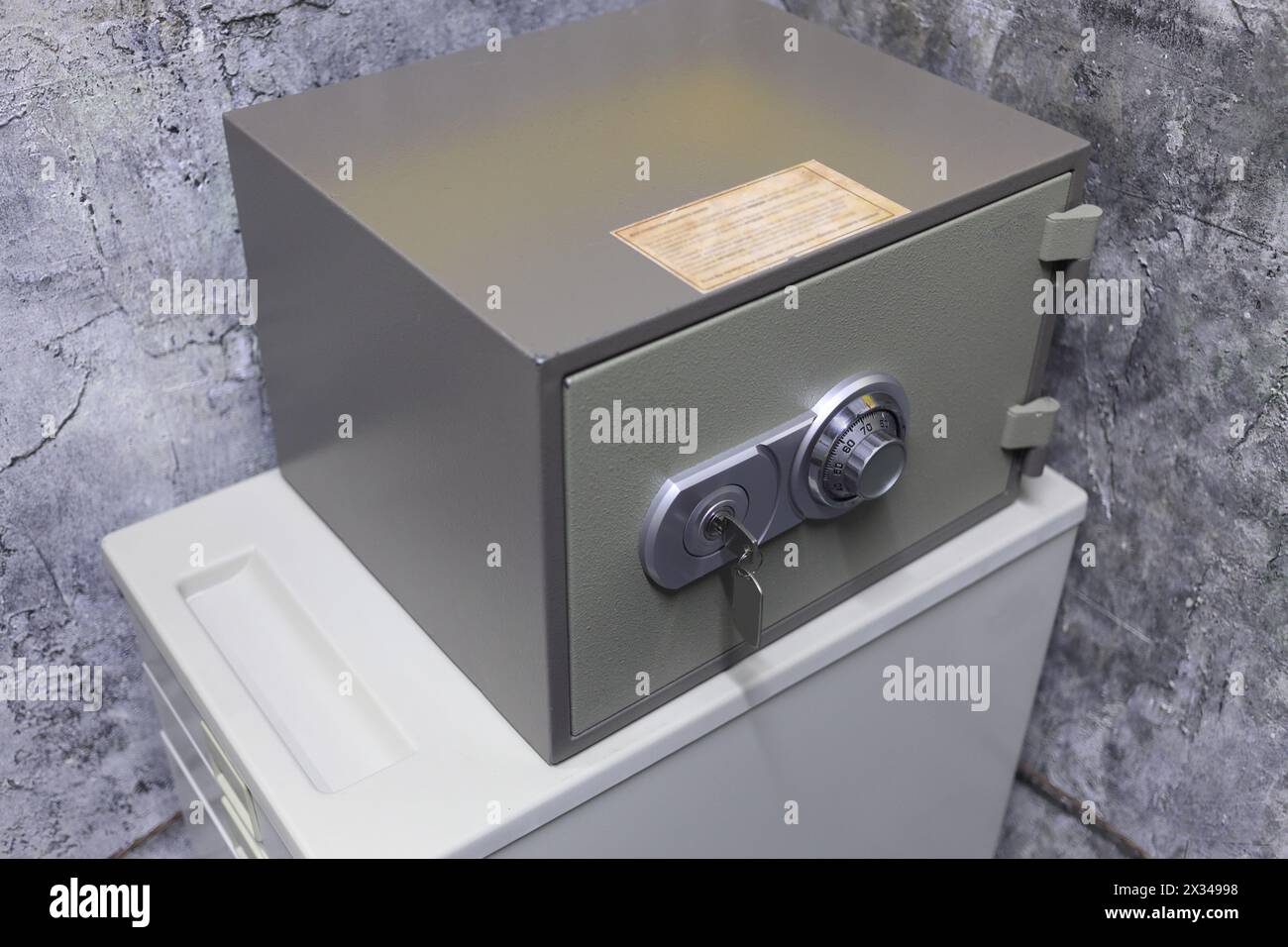 small metal safe with key and combination lock on box in corner of room ...