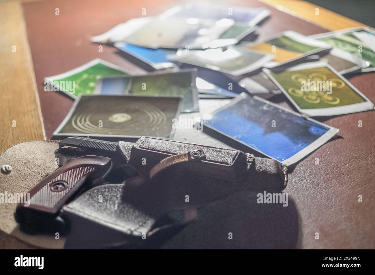 plastic pistol in leather holster with crumbled cards on table Stock ...