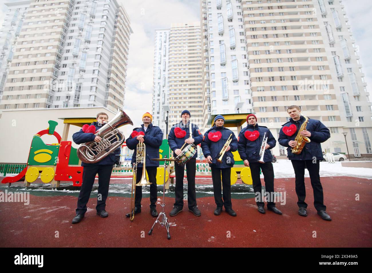 Brass band of six musicians pose on playground near buildings at winter ...