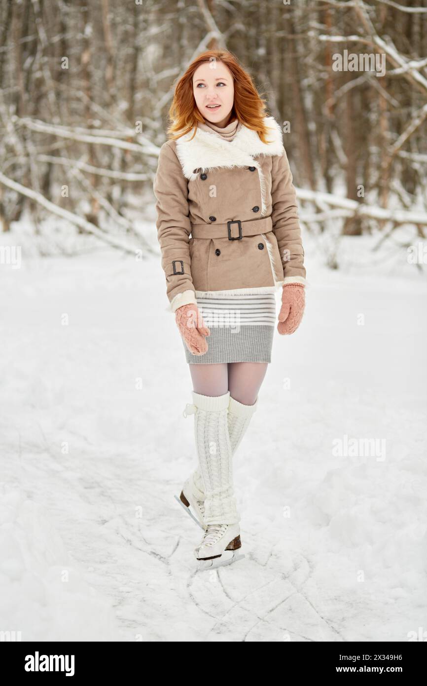 Teenage girl with braces on teeth stands on skates on ice pathway in ...