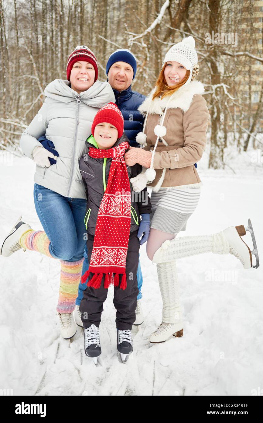 Happy family of four stands embracing on skates on ice pathway in ...