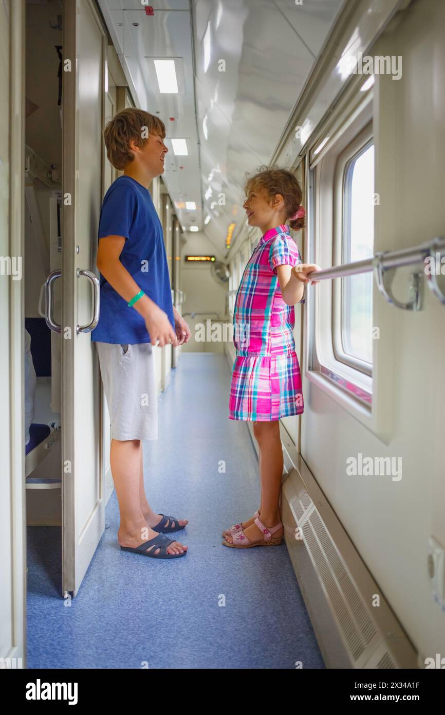 Brother and sister standing in corridor train compartment and laughing ...