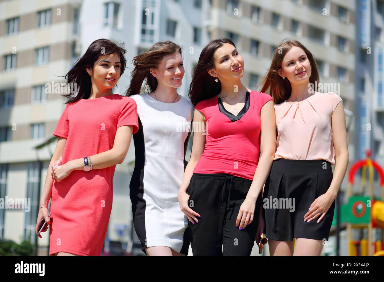 Four happy pretty girls pose outdoor on street at sunny summer day ...