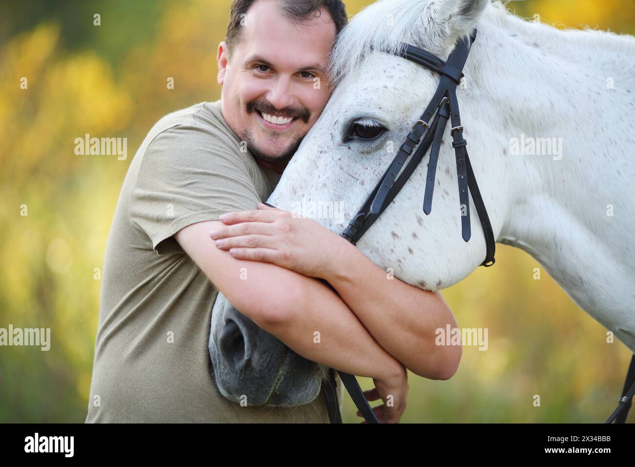 Happy smiling man hugs beautiful white horse head in autumn park Stock ...