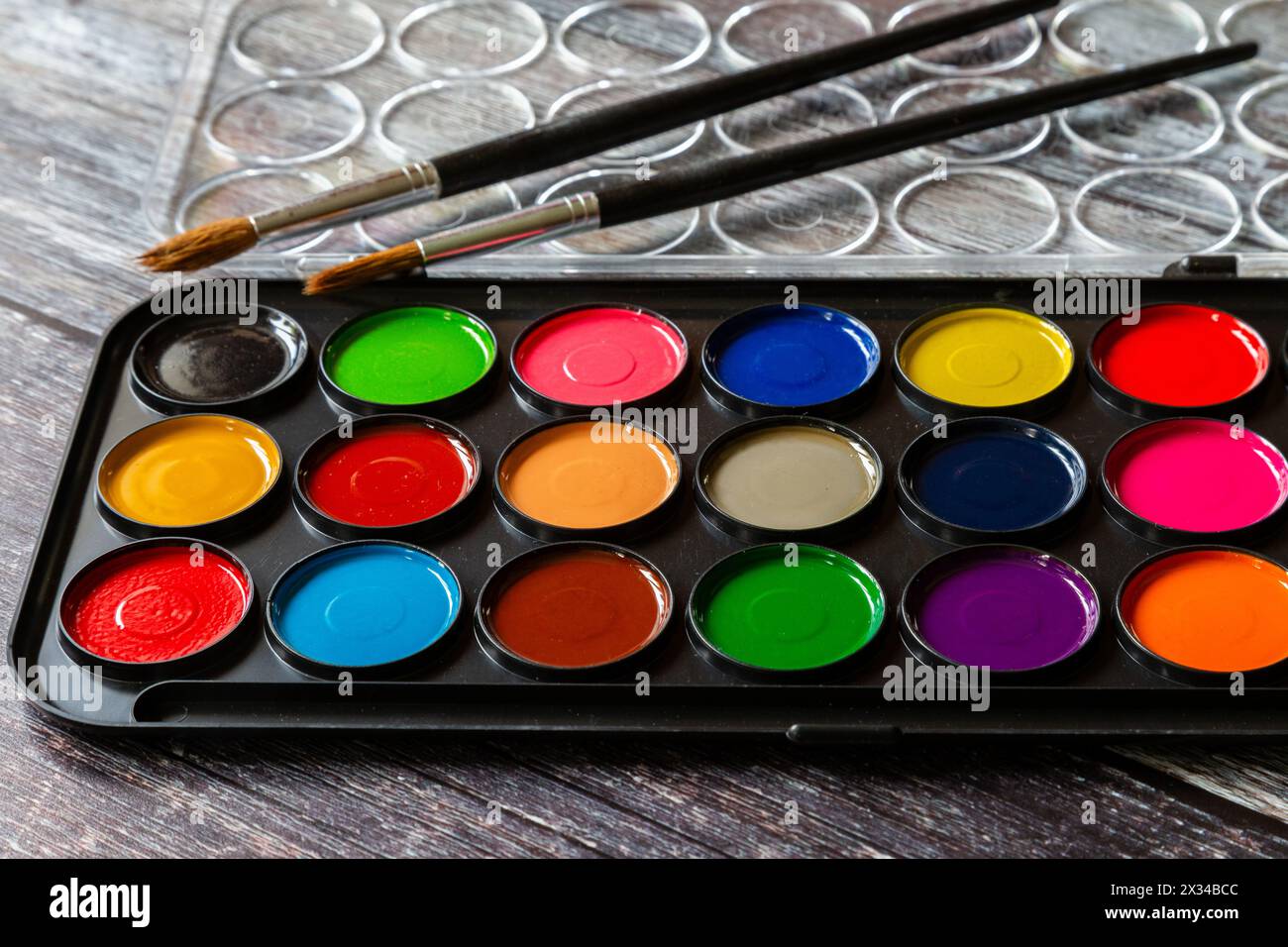 A pallet of paints for water colour art. Two artists paintbrushes lay ...