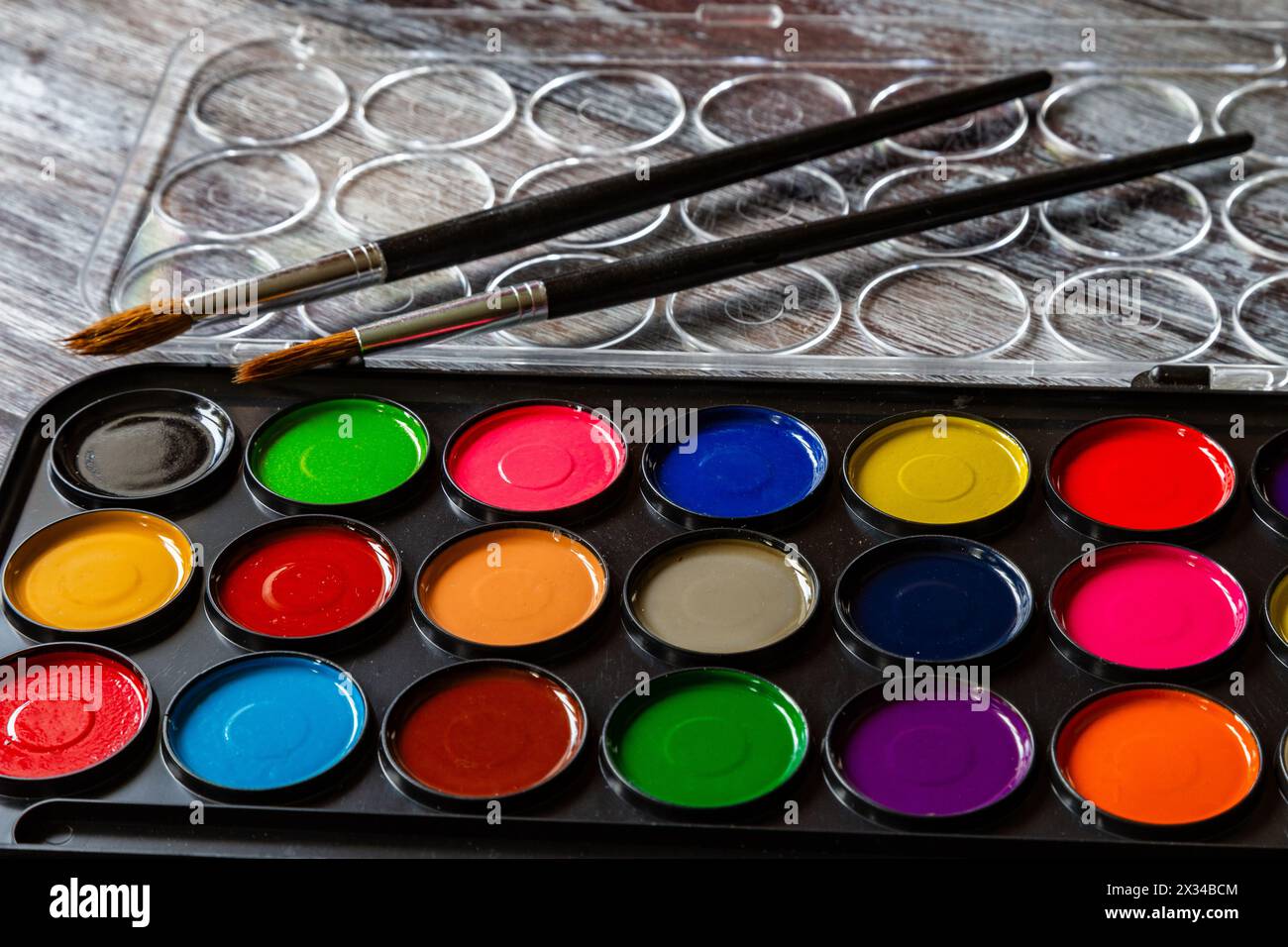 A pallet of paints for water colour art. Two artists paintbrushes lay ...