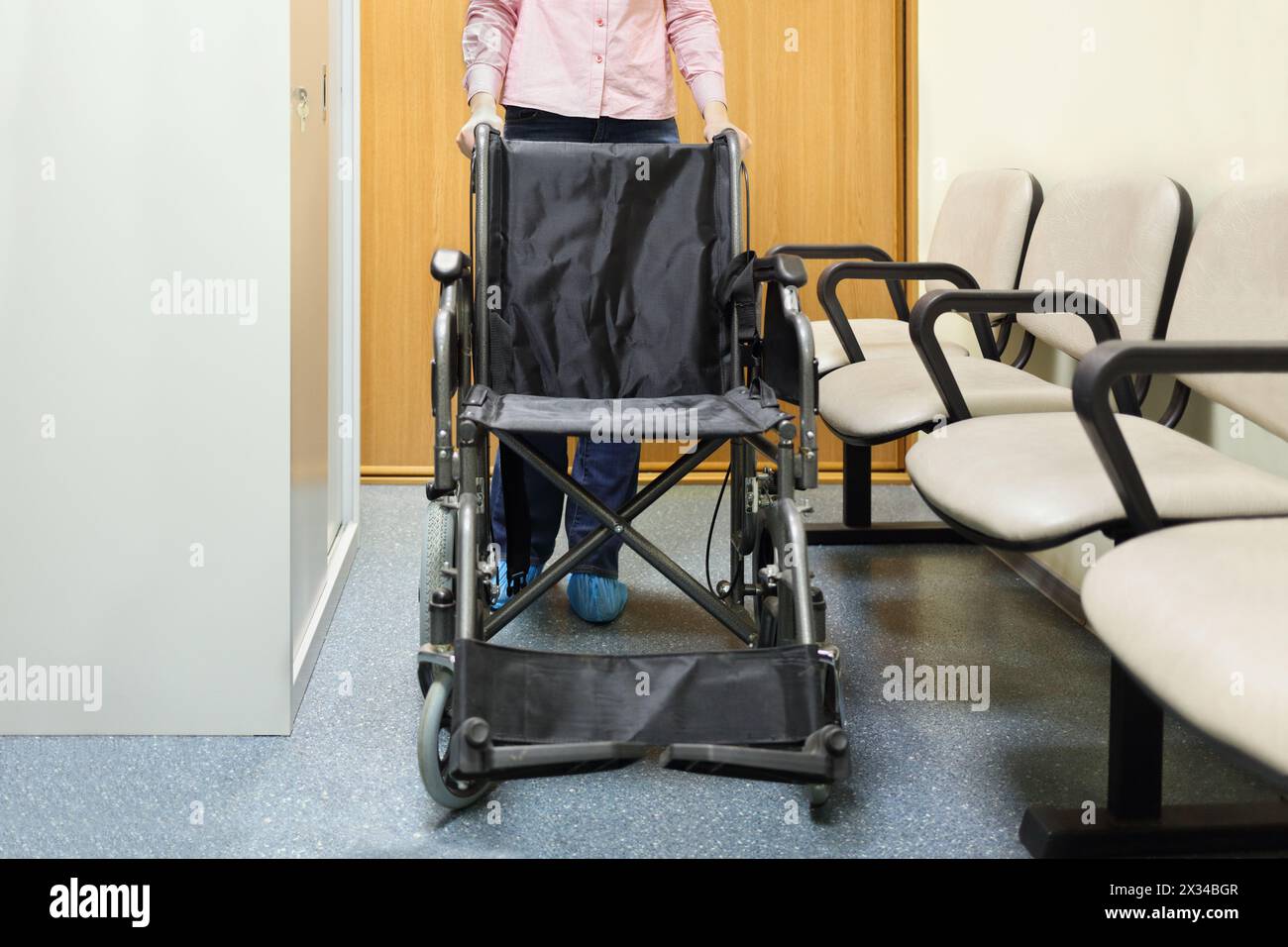 woman holding on to handle wheelchairs standing in lobby of hospital ...