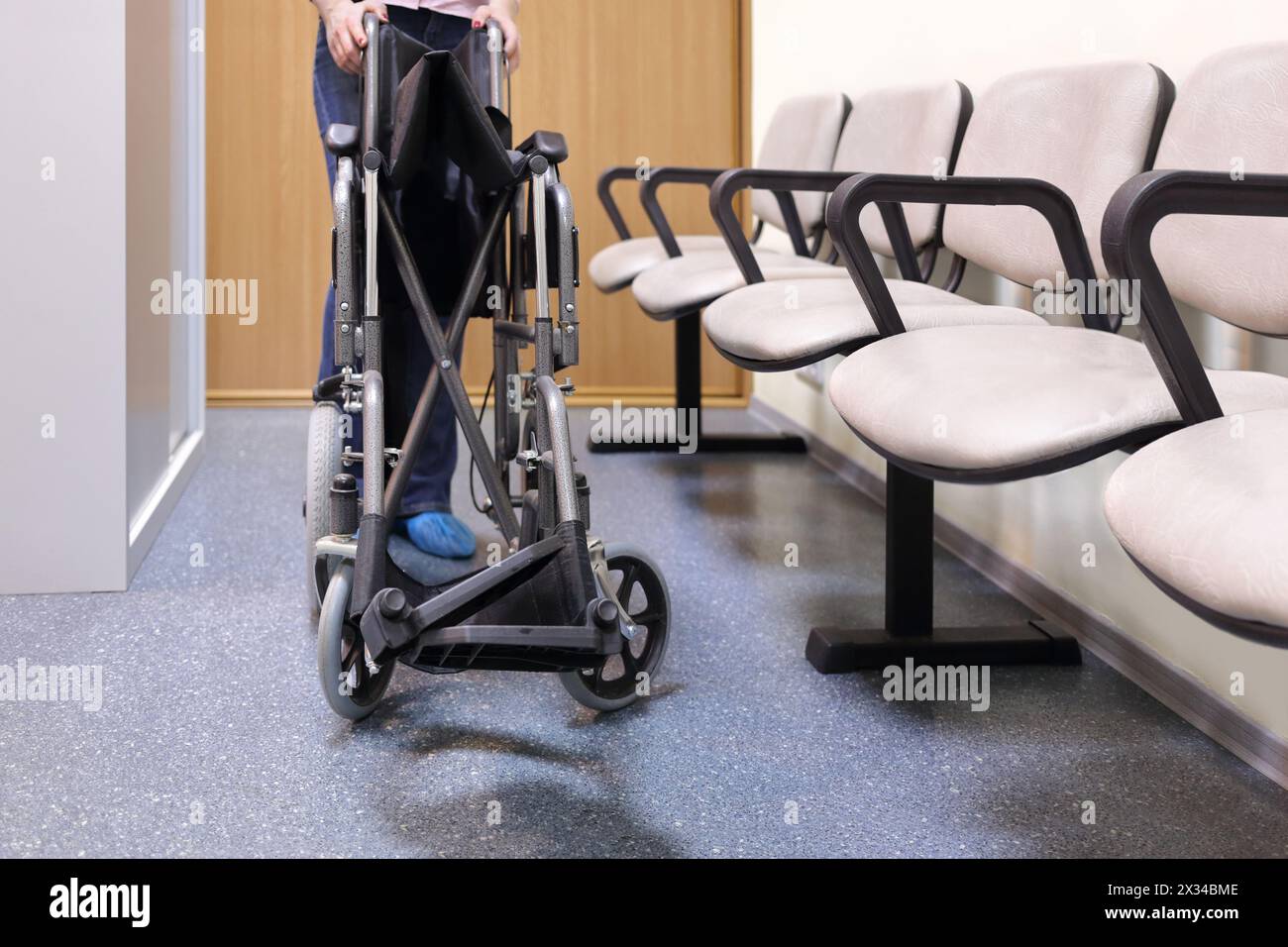 woman folds or unfolds black wheelchair in lobby of hospital Stock ...
