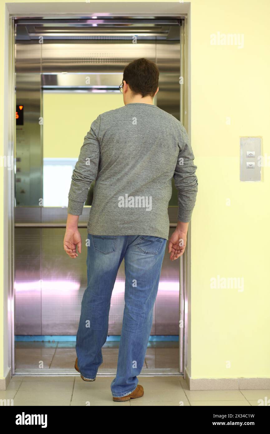 Man in jeans walking into an open elevator, view from the back Stock ...