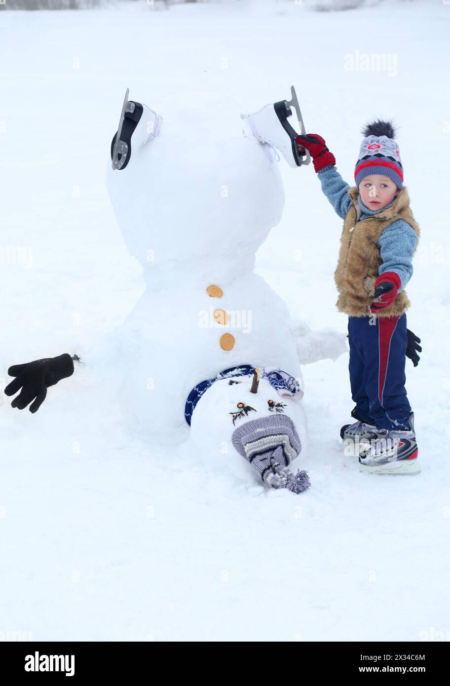 Little handsome boy stands near upside down snowman at winter day Stock ...