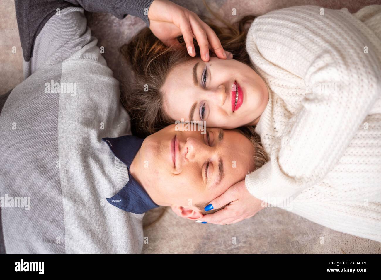 A contented couple lounging on a carpet, their intimacy captured in a ...