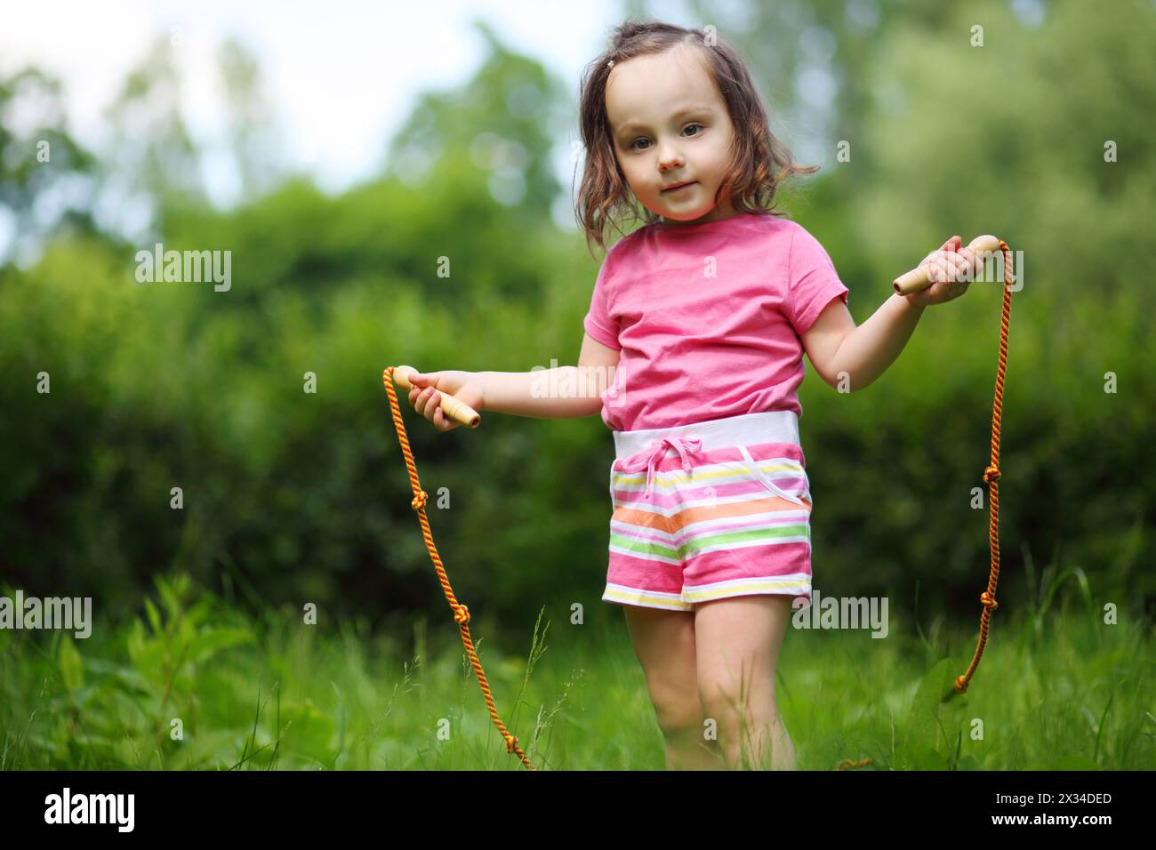 Little cute girl poses with skipping rope in summer sunny garden Stock ...