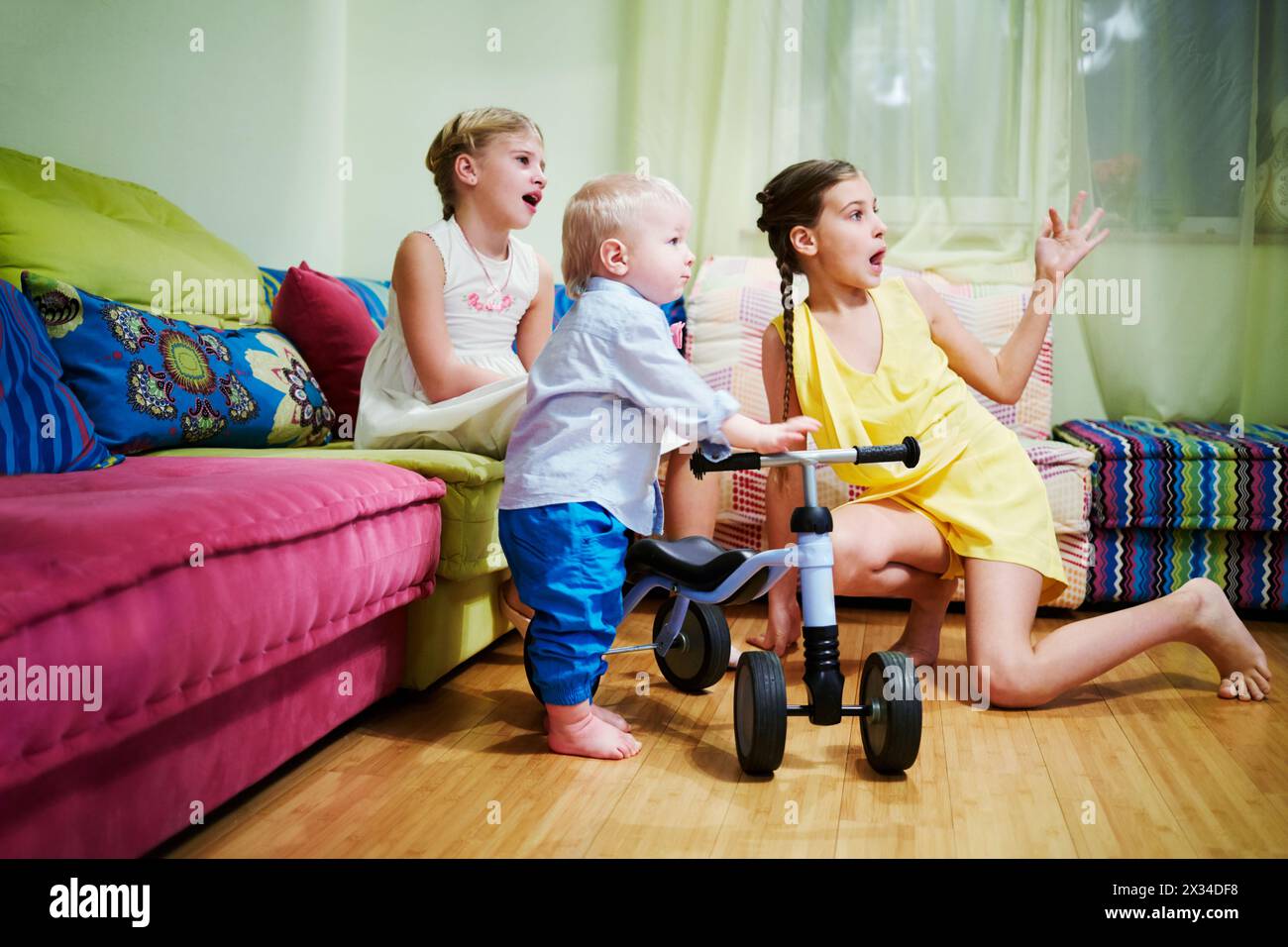 Little boy with small bike and two girls look amazed at something ...
