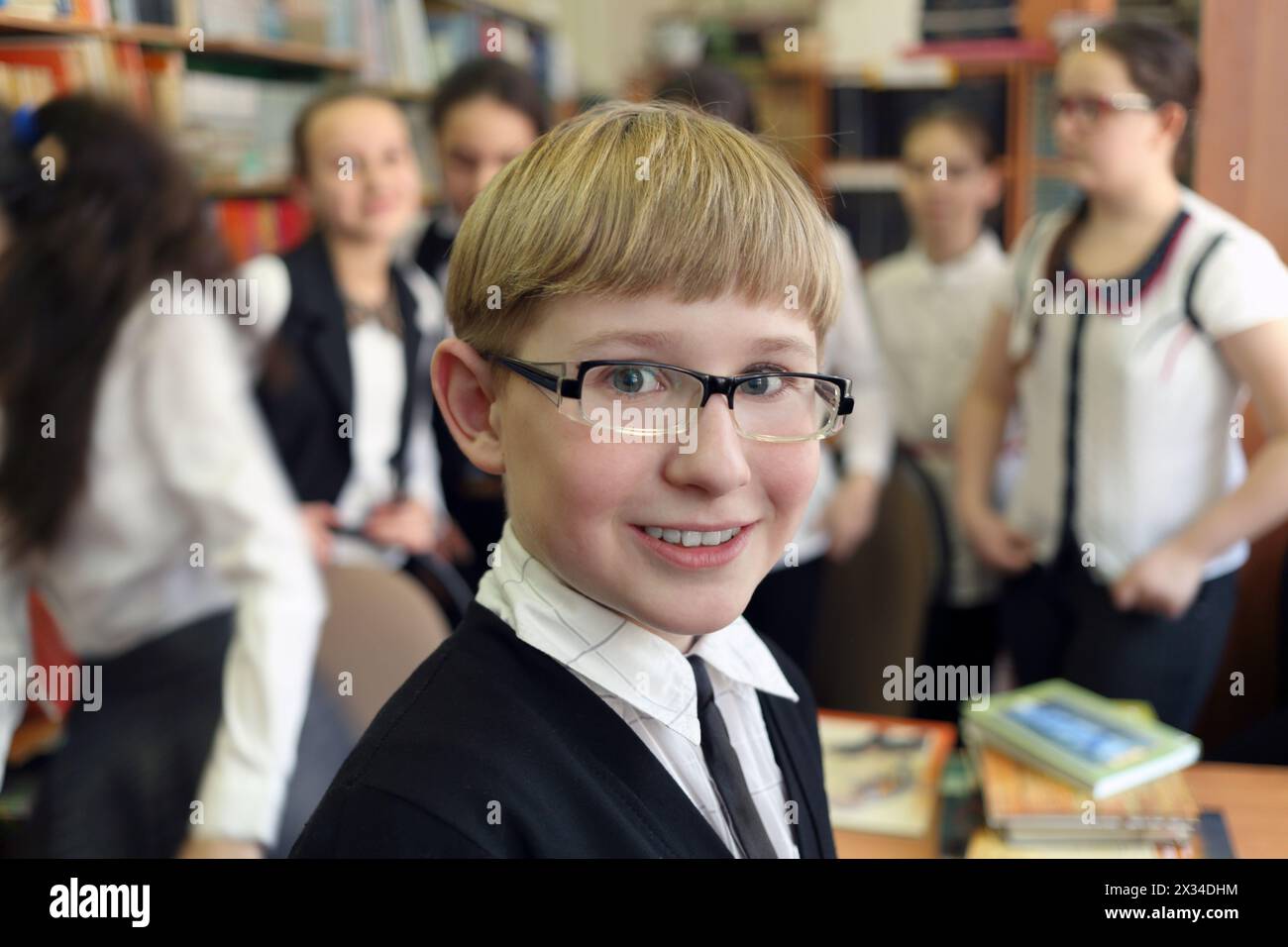 student in black jacket and glasses on background of shelves with books ...
