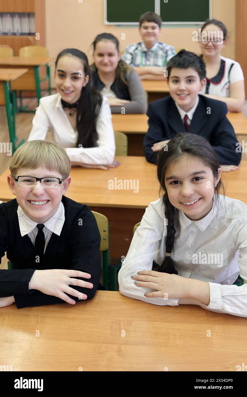 three boys and four girls in classroom sitting at desk in classroom ...