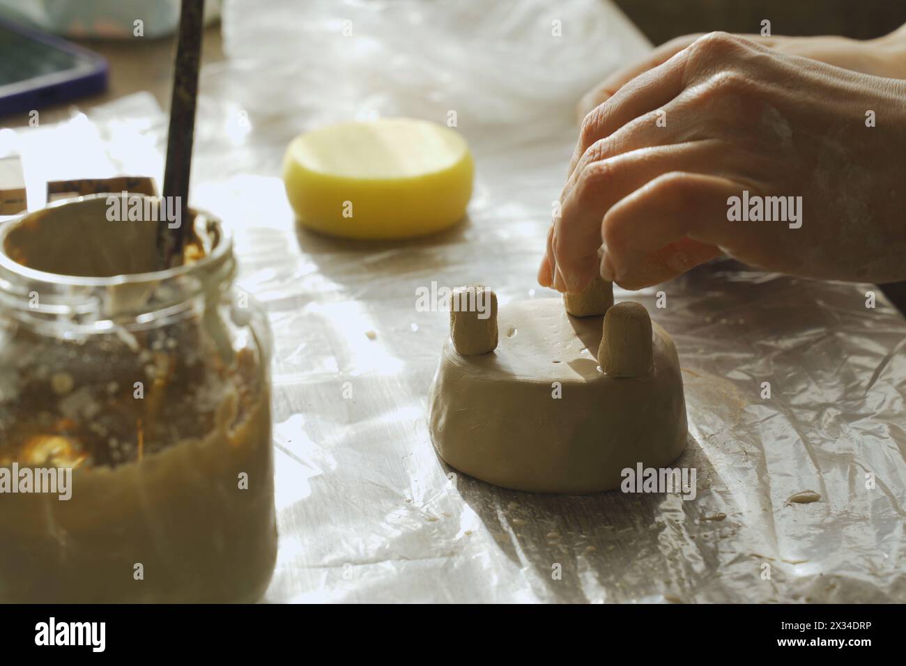 A woman makes a ceramic pot and attaches the legs. Close-up. Creative ...
