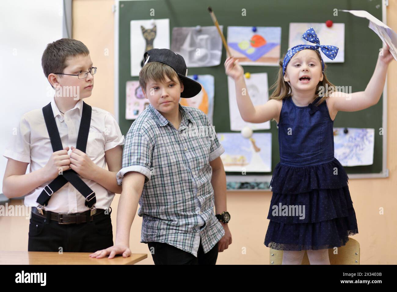 three students: two boys and one girl act out scene in class ...