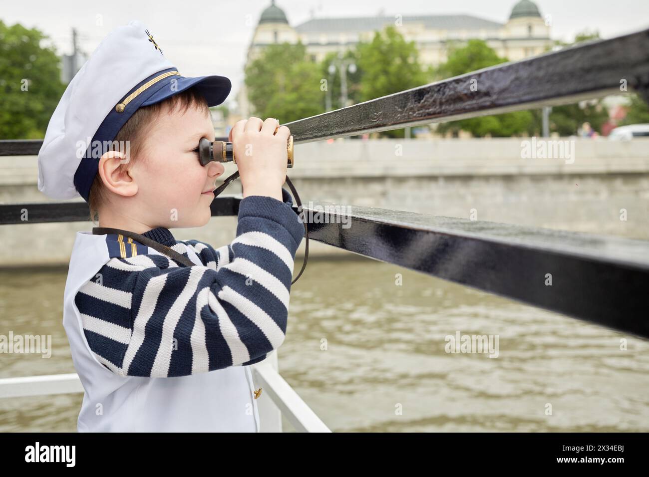 Little boy dressed as a captain looks through binoculars standing at ...
