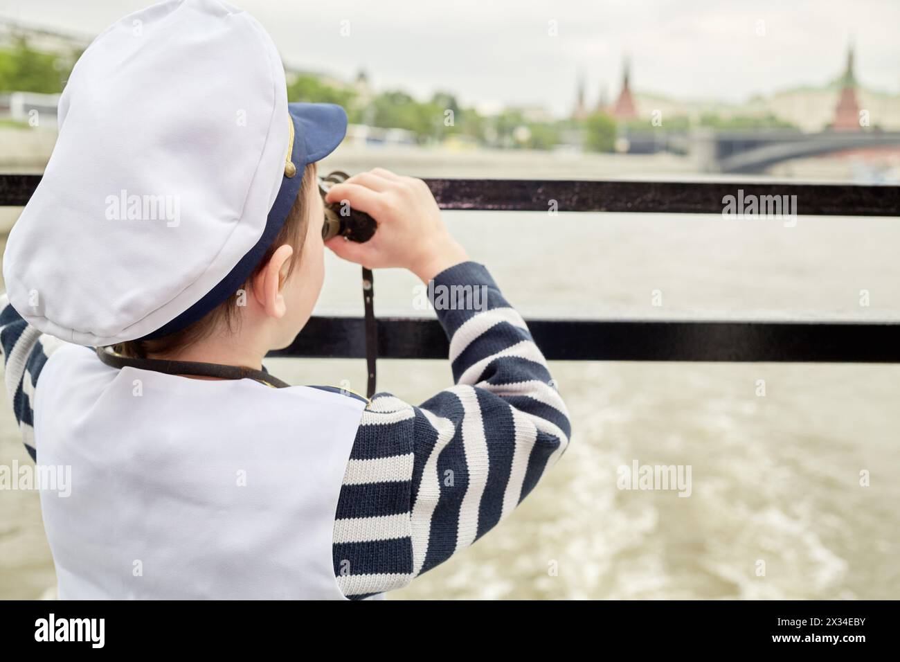 Little boy dressed as a captain looks through binoculars standing at ...
