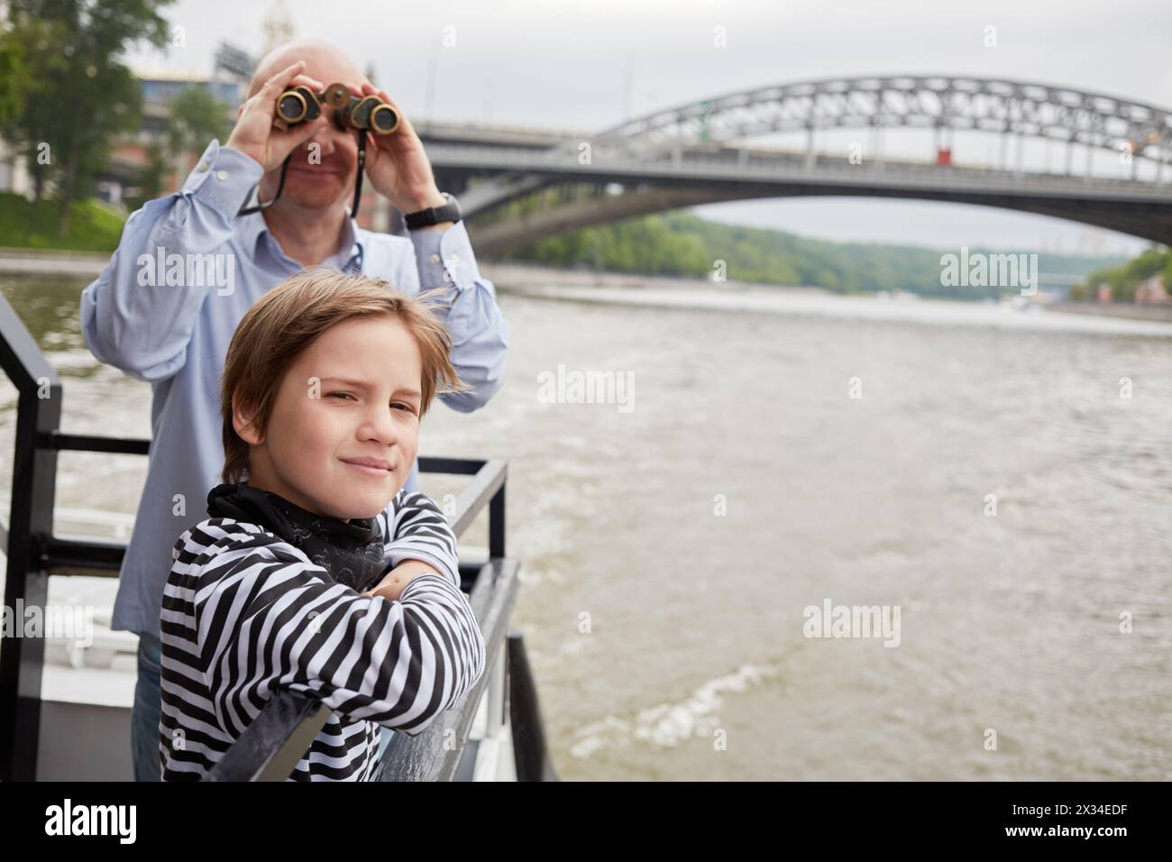 Boy and man stand on the deck, man looks through binoculars Stock Photo ...