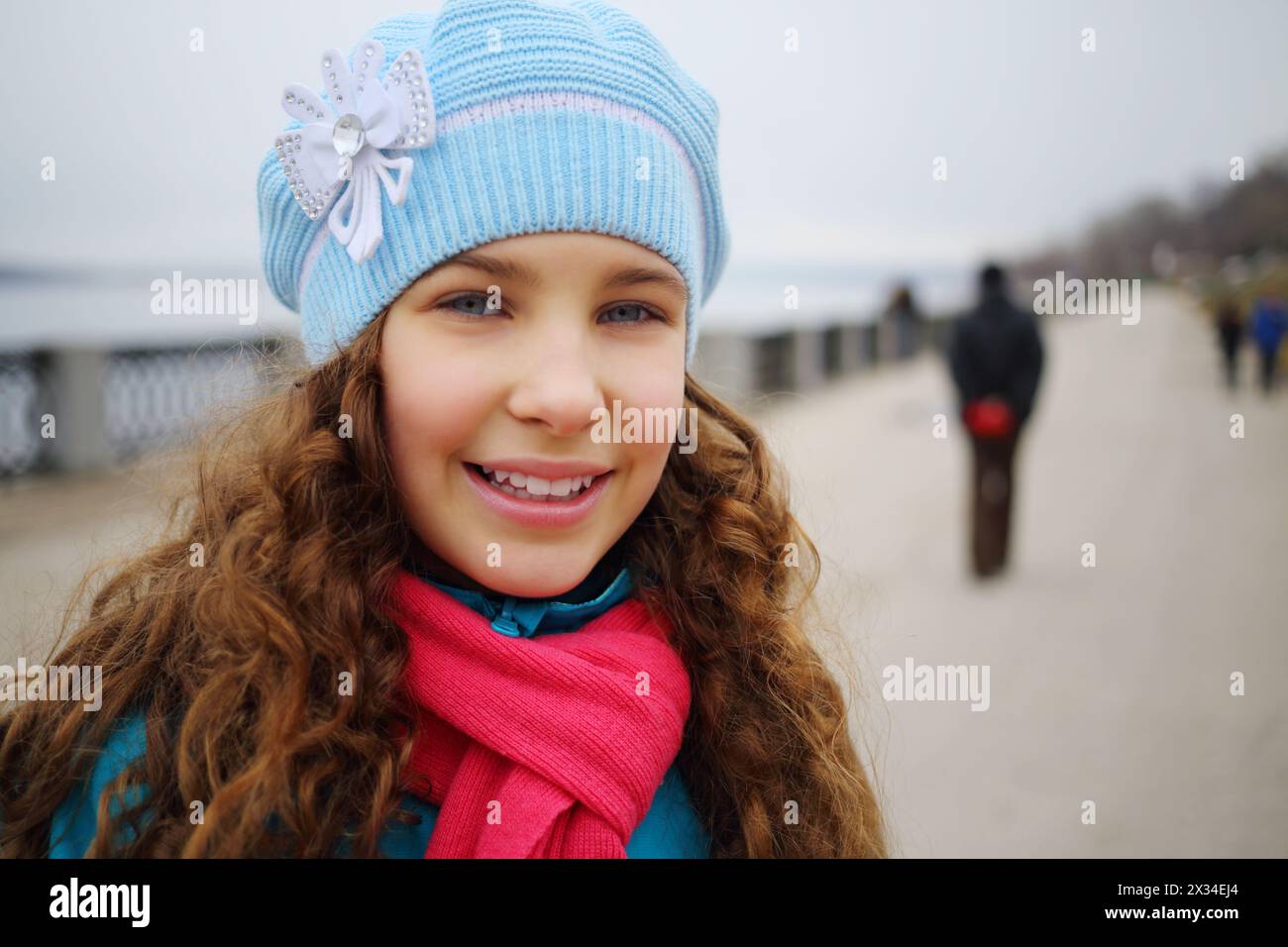 Happy girl in blue hat poses on river embankment at spring day, shallow ...