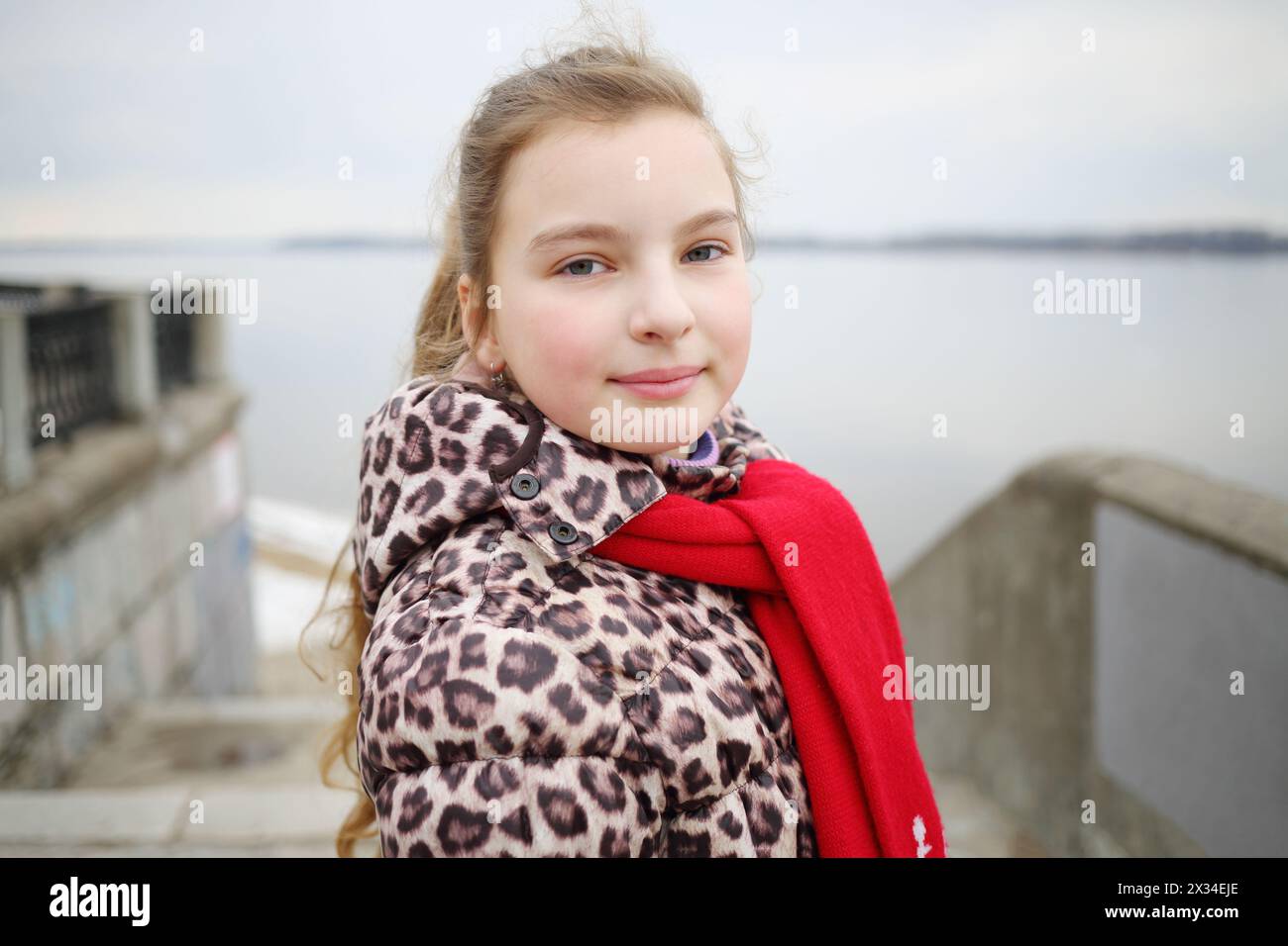Girl in red scarf poses on river embankment at spring day, shallow dof ...