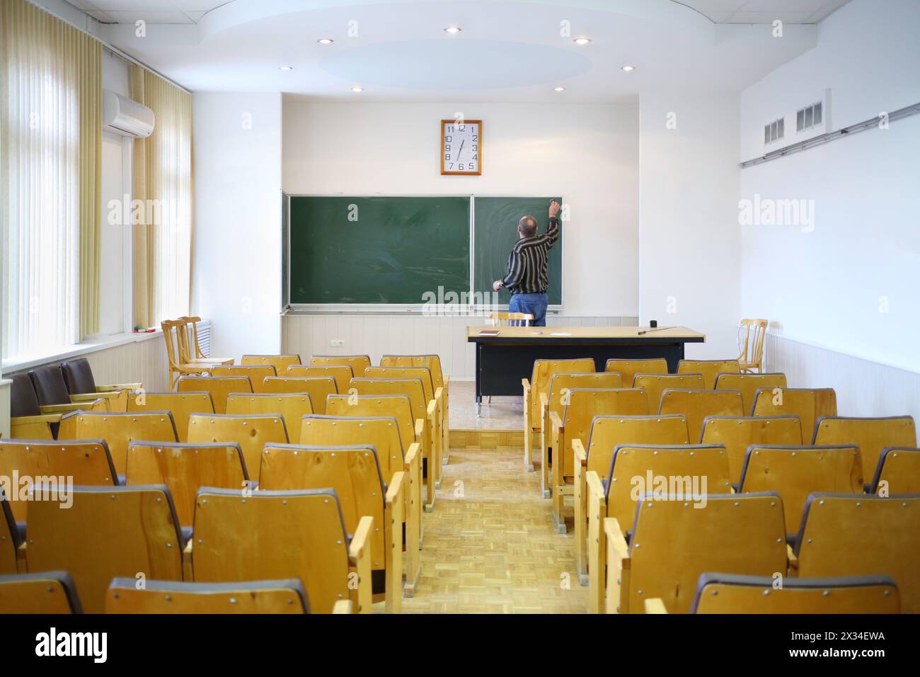 Teacher clears with blackboard in empty classroom, back view Stock ...