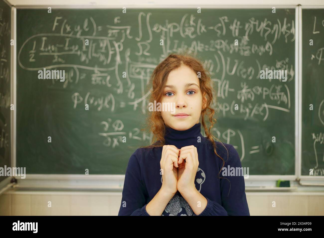 Pretty girl clasped her hands in heart shape near blackboard with ...