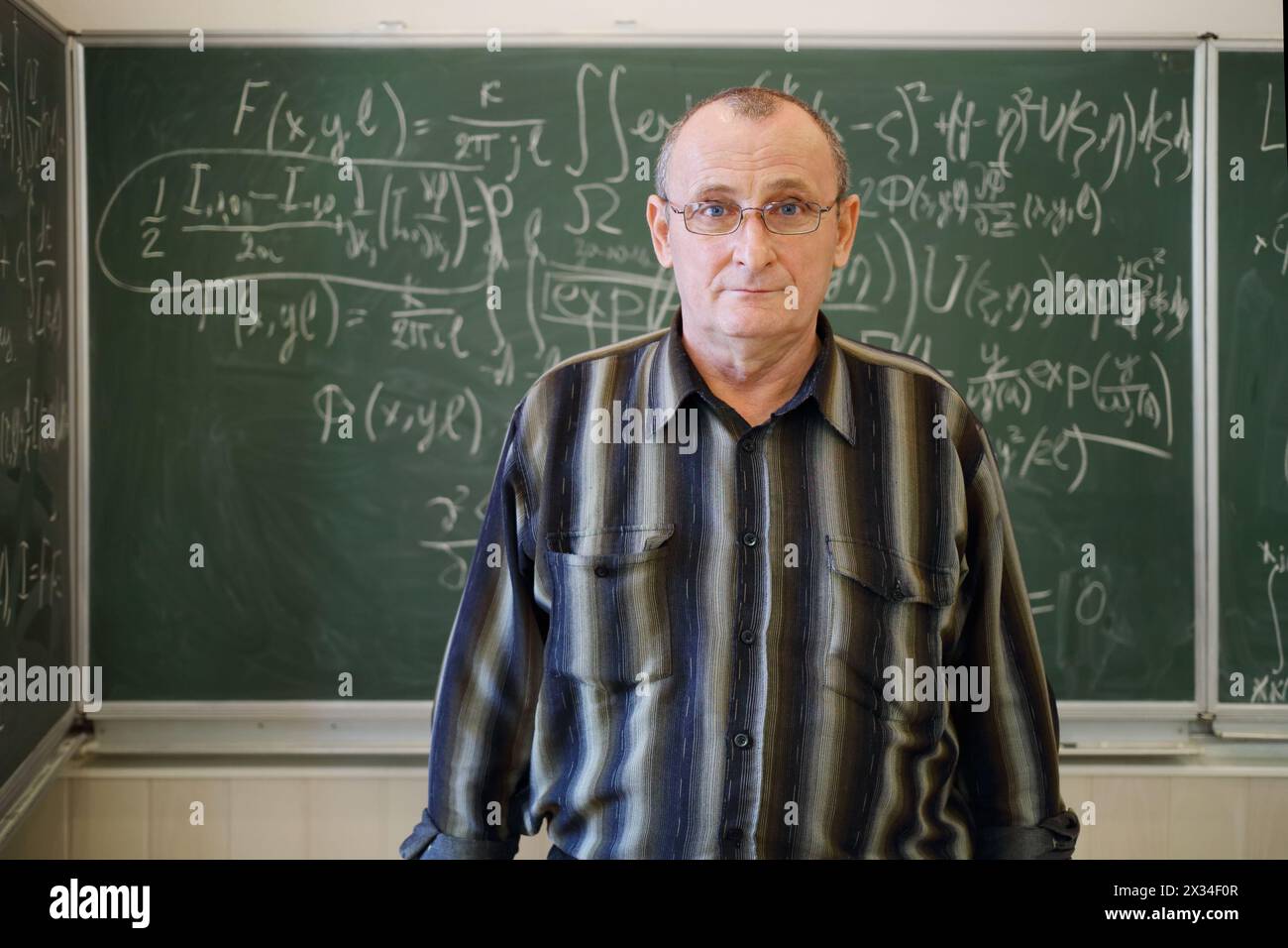 Teacher stands near blackboard with mathematics formulas in school ...