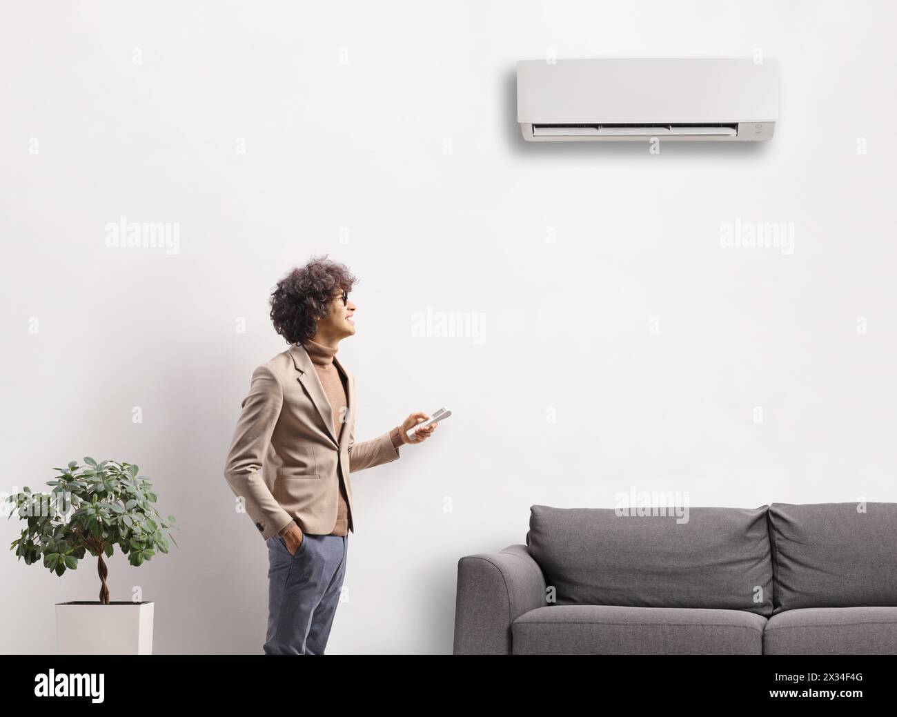 Young man holding a remote controller from an air conditioning unit at ...