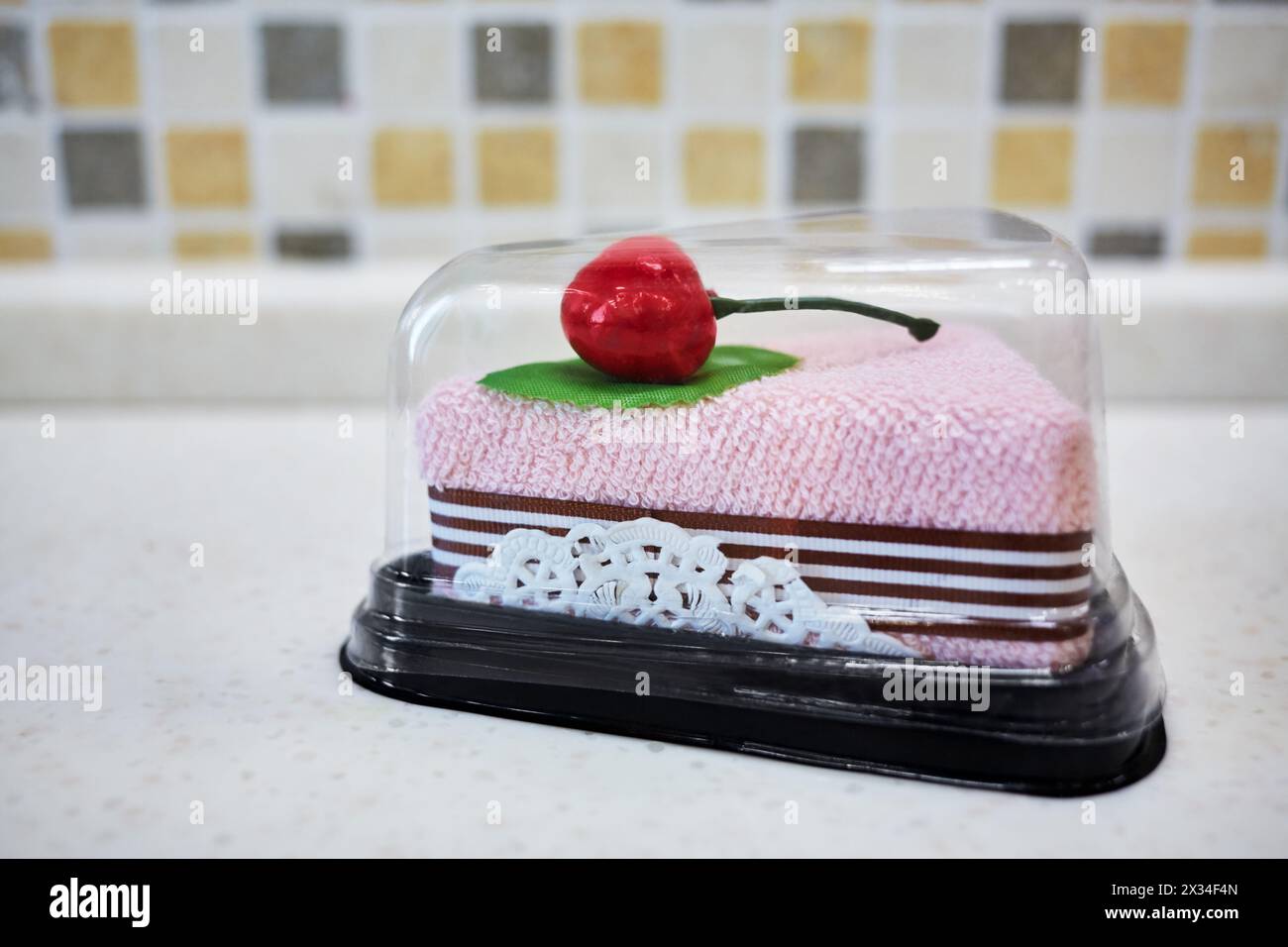 Kitchen sponge in a form of cake decorated with cherry in plastic box ...
