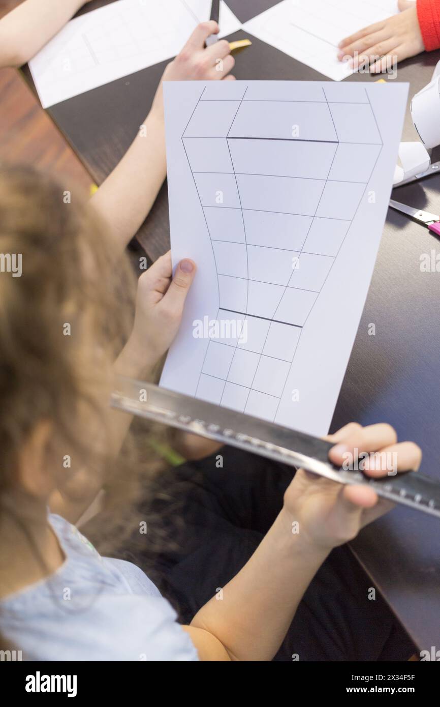 Girl with a sheet of paper and a ruler in hands making crafts Stock ...