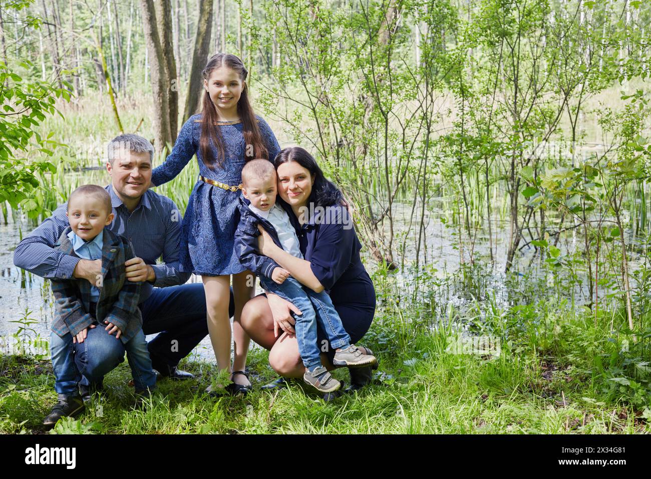 Family of five poses on boggy pond shore in summer park Stock Photo - Alamy