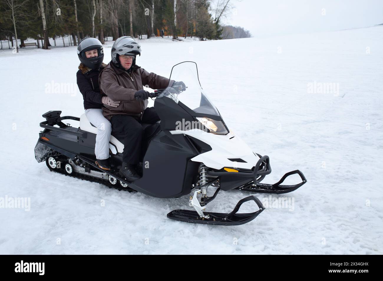 Father with young daughter riding on a snowmobile Stock Photo - Alamy