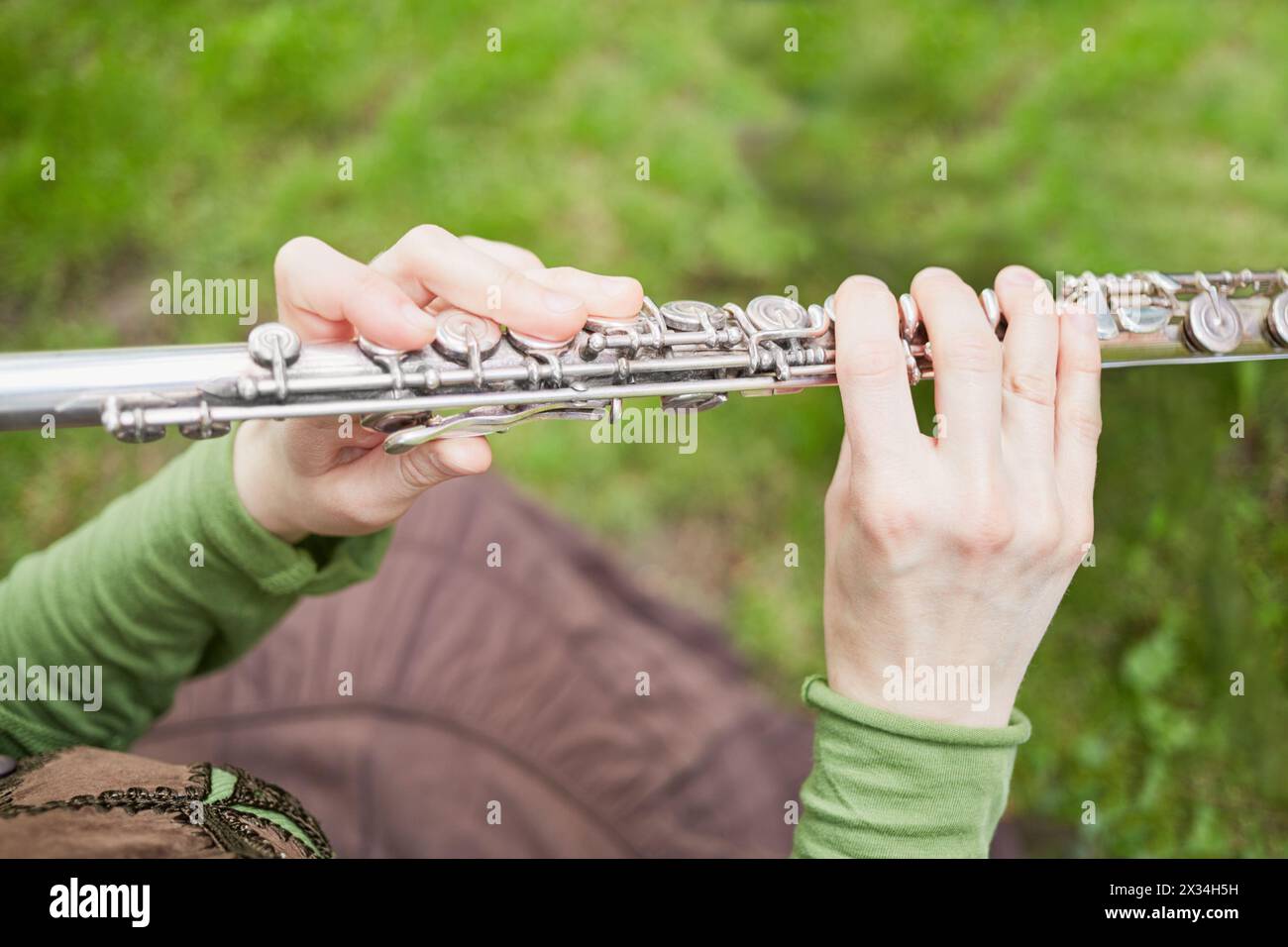 Female hands hold metal flute against green grass Stock Photo - Alamy