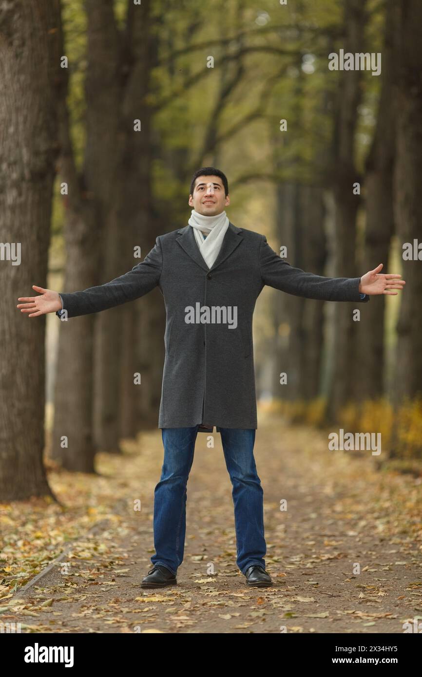Portrait in full growth young man in gray coat with outstretched hands ...