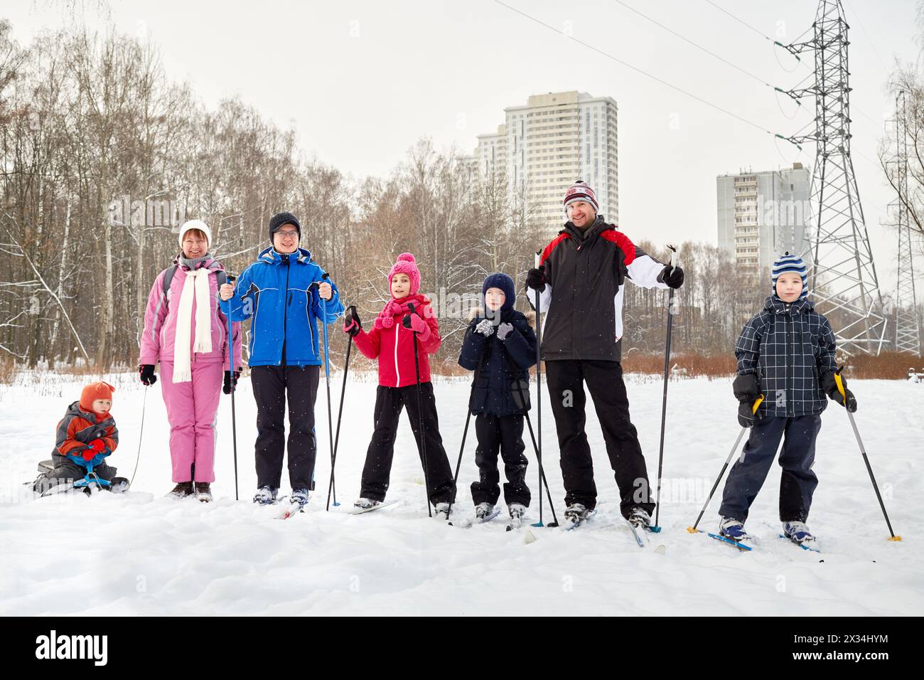 Group of seven people three adults and four children on skis and sledge ...