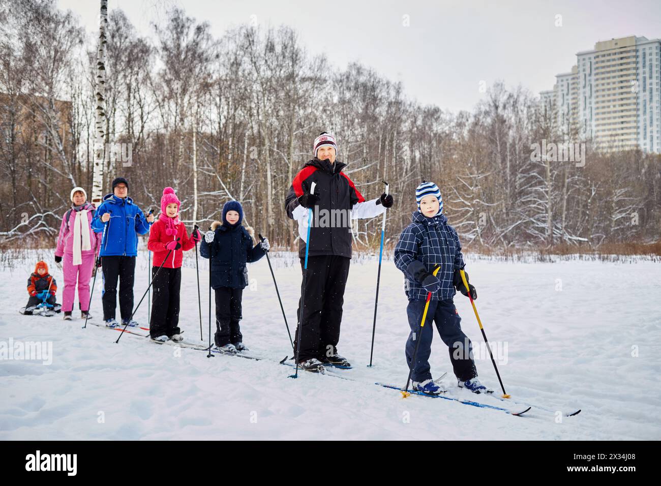 Group of seven people three adults and four children slide on skis and ...