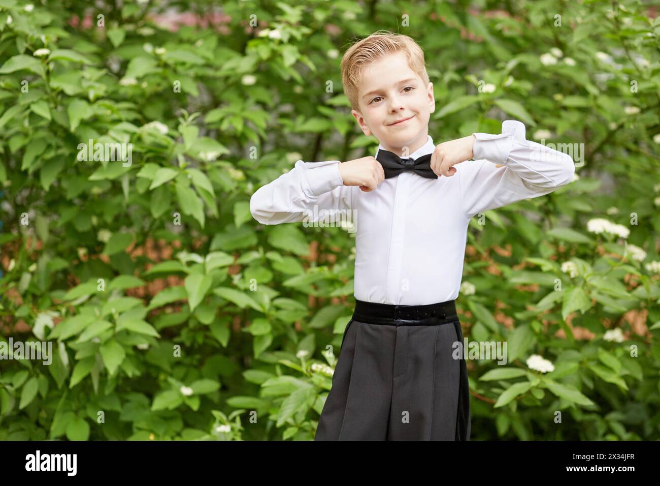 Little boy dressed in dance suit adjusts bow standing outdoor Stock ...