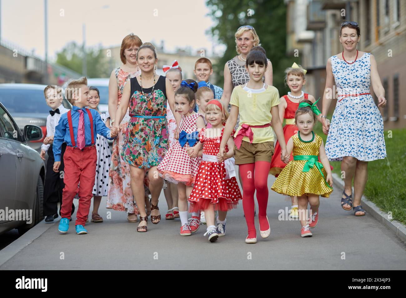 Group of eleven children and four woman walks down street Stock Photo ...