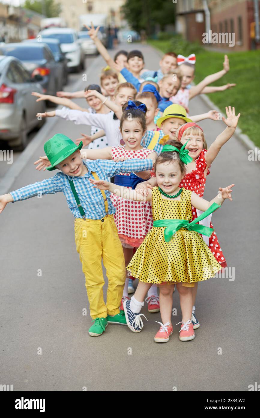 Fifteen children stand one by one outstretching arms to sides at ...