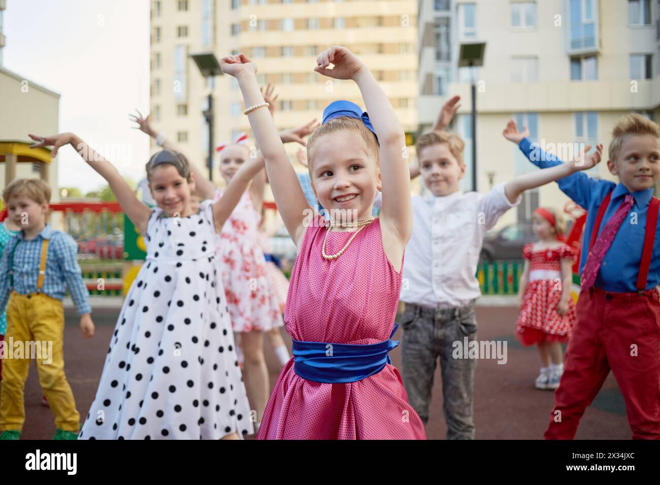 Eight little children dance at playground in courtyard, focus on first ...