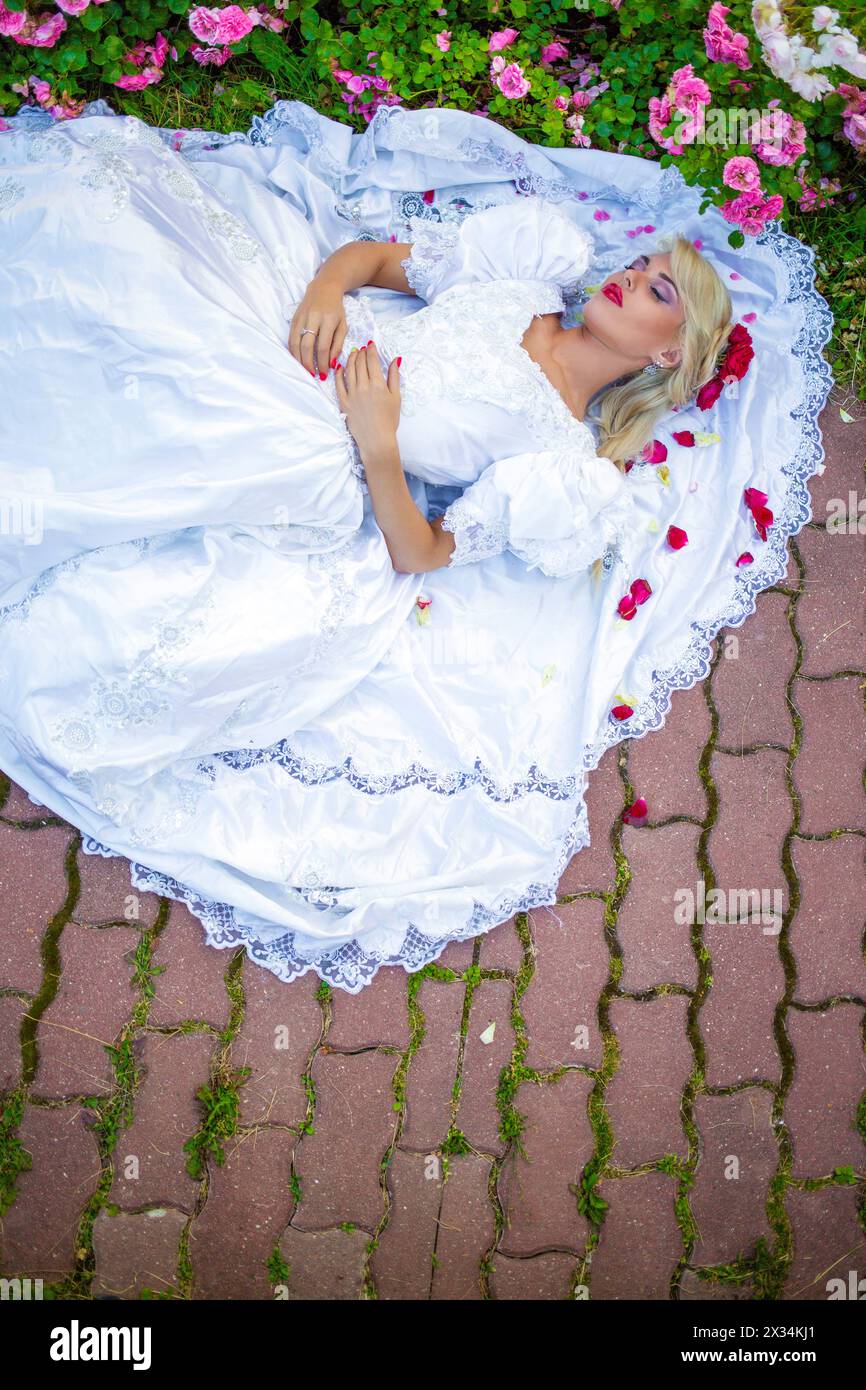 portrait of beautiful woman in white dress lying on walkway and ...