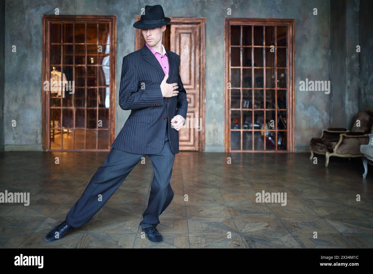 Man in suit dances tango in retro room with wooden doors and big ...
