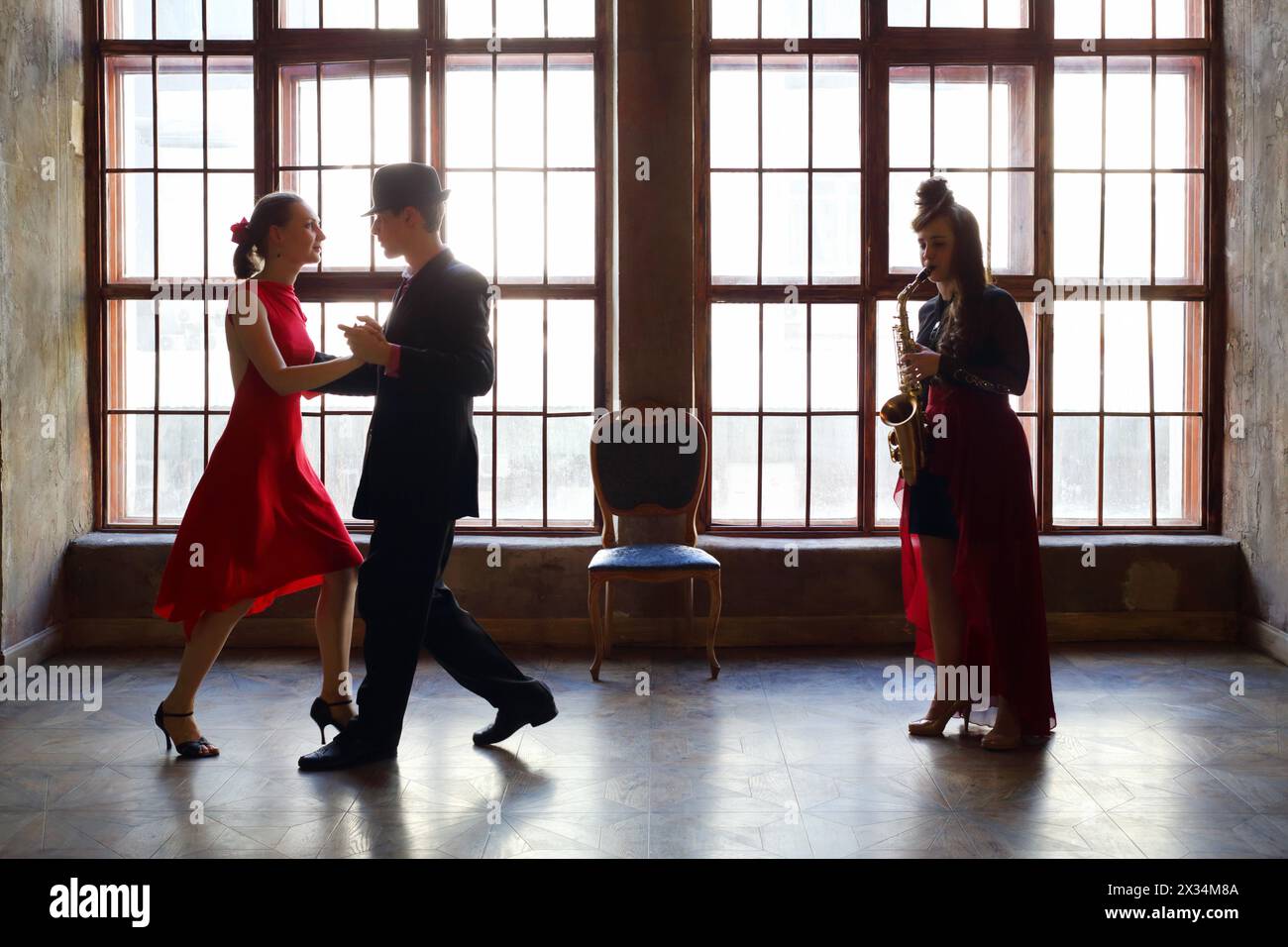 Girl plays sax and beautiful couple dance tango near big window Stock Photo - Alamy