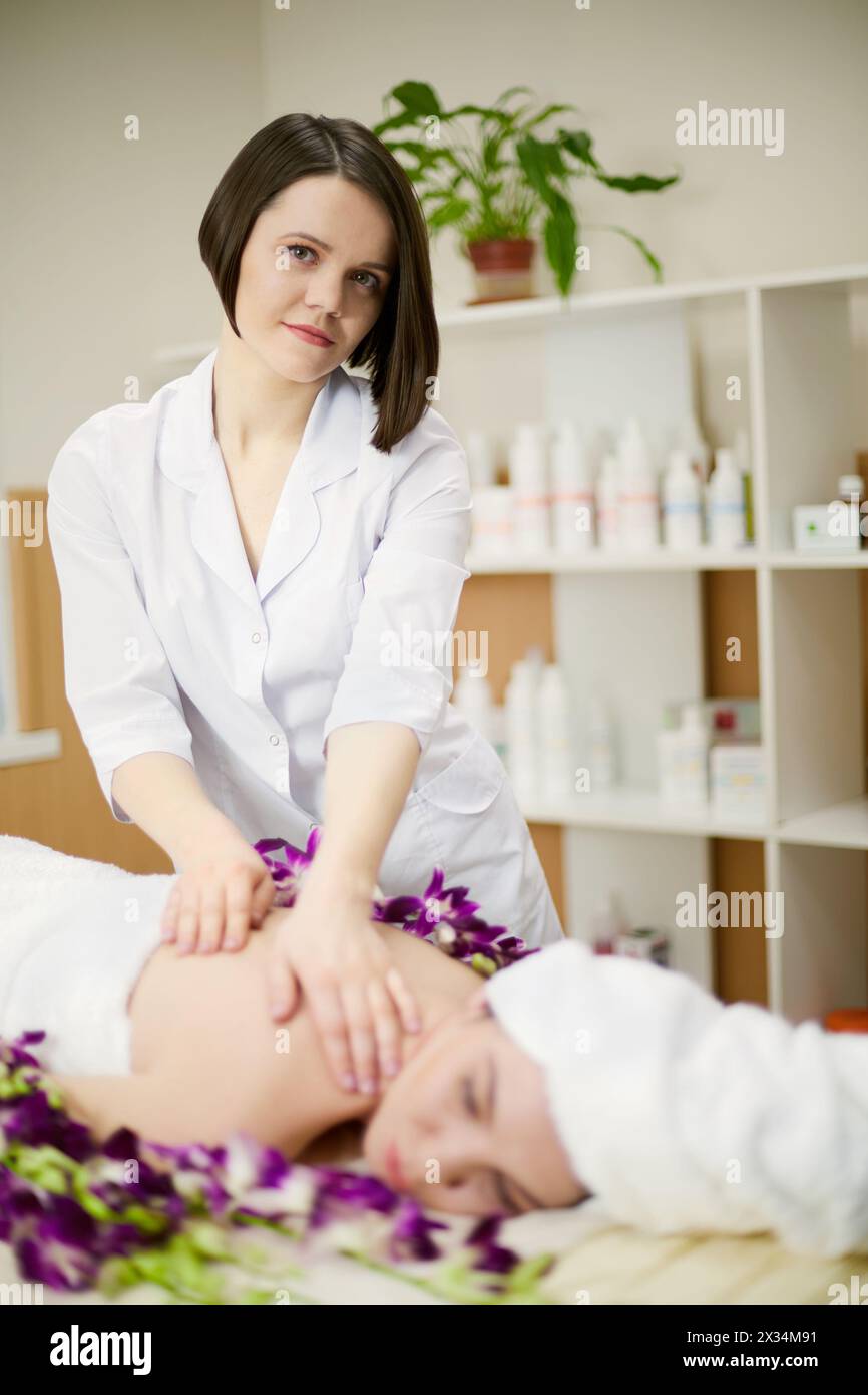Female massage therapist do back massage of woman lies on couch with ...