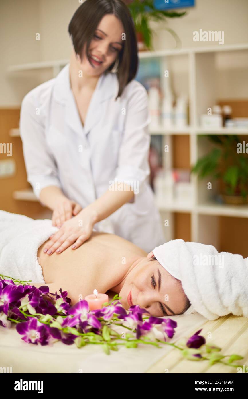 Female massage therapist do back massage of woman lies on couch with ...