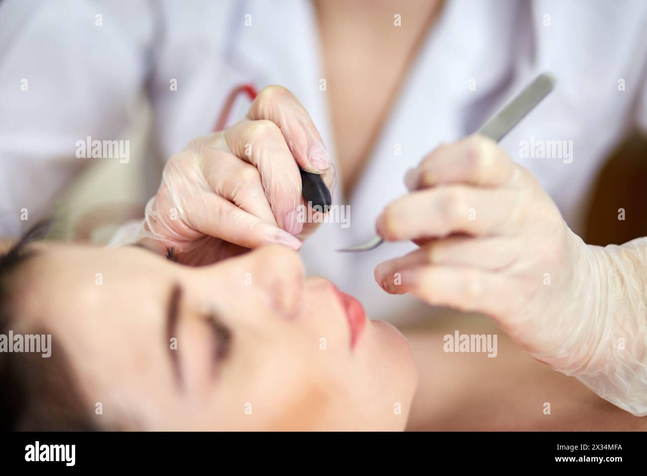 Hands in rubber gloves of beautician that hold instruments for doing ...