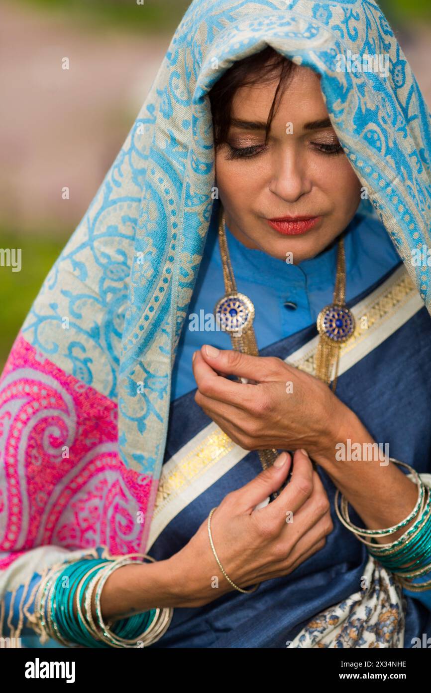 Sad indian woman stands and looks down in bright sari in garden Stock ...