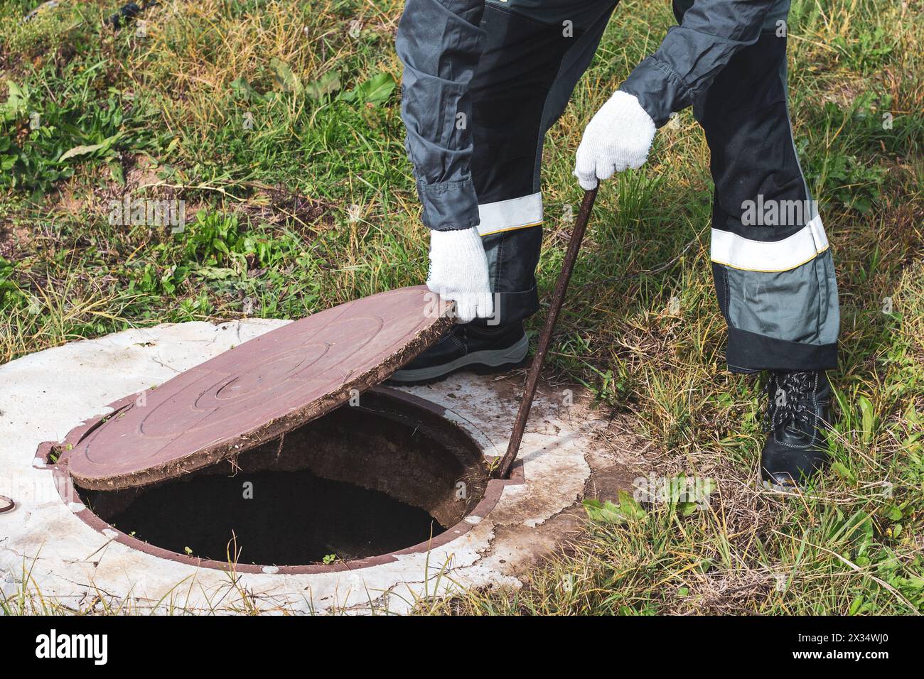 On a septic sewer well, a worker opens the manhole cover. Plumbing work ...